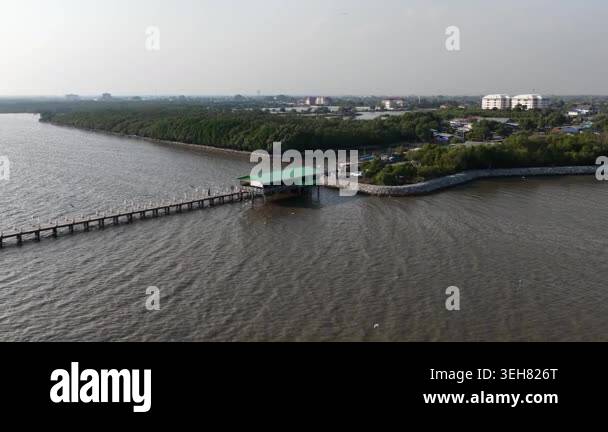 Aerial view of a pier extending into a river at its mouth, with a ...