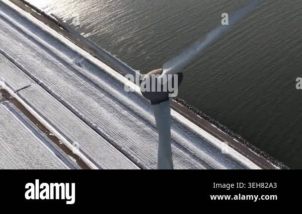 Aerial footage showing a wind turbine rotating as the camera moves away ...