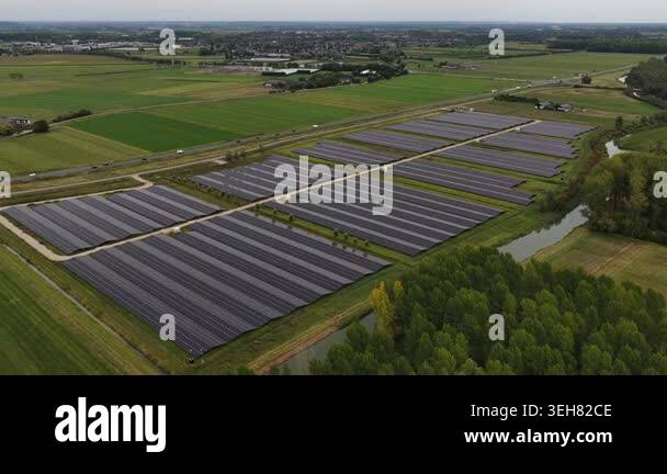 Aerial footage of a modern solar farm with rows of photovoltaic panels ...