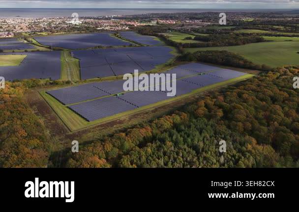 Sweeping aerial perspective of a large solar panel farm nestled in the ...