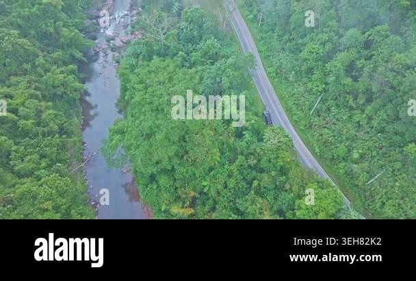 Aerial view of a winding road along a river surrounded by lush green ...