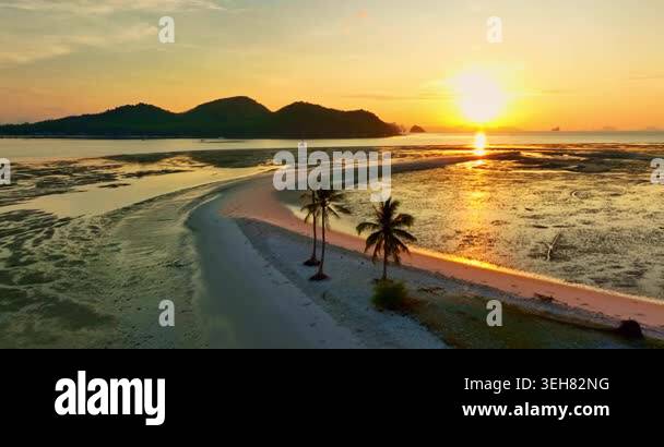 Scenic tropical beach at sunset with palm trees and hills in the ...