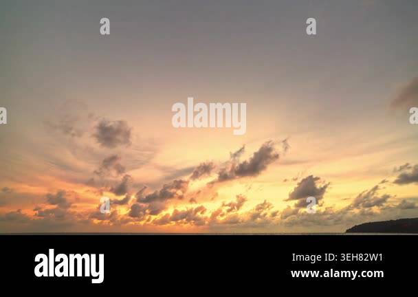 Time lapse sky turns yellow to orange and red over the sea.The sun rays ...