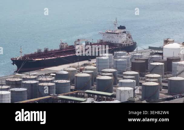 Massive oil tanker moored at an industrial port terminal, with numerous ...