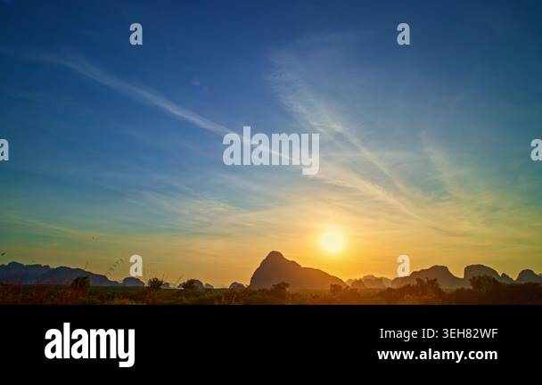Sun setting over a mountain, illuminating the sky in warm colors with ...