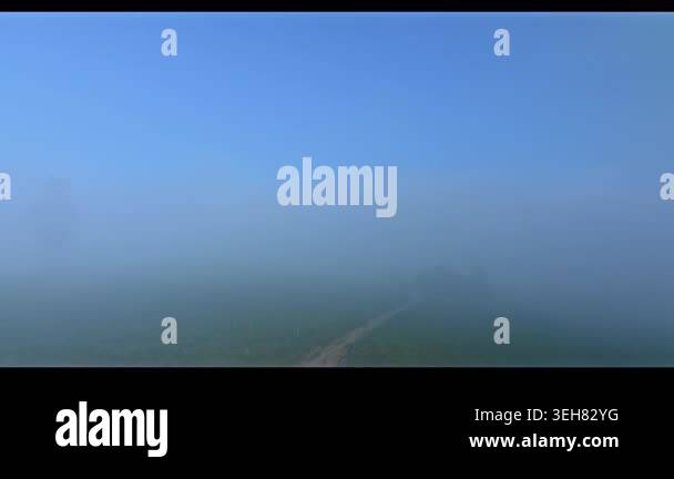 Aerial view of a foggy landscape with a distant road disappearing into ...