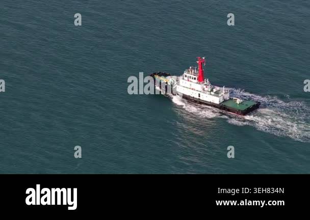 Powerful tugboat maneuvering across the calm, dark blue ocean, creating ...
