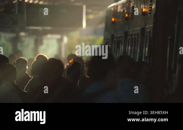 People stand and wait at the train station as a train approaches. The ...