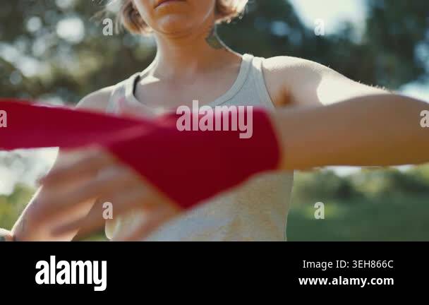 Professional female fighter wrapping her hands with red hand wraps ...