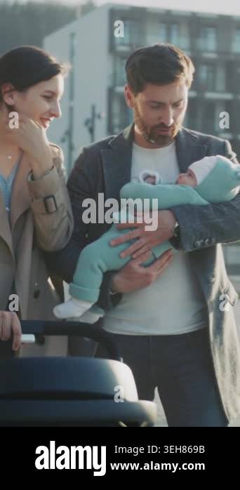 parents walking with baby at urban waterfront, father holding infant ...