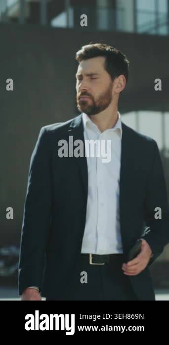 white bearded executive in navy suit walking through modern city plaza ...