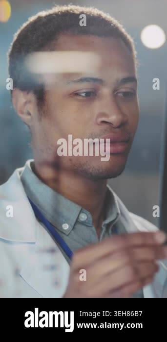 black male doctor reviewing radiograph, closeup portrait in lab coat ...