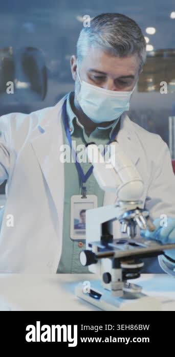 Caucasian technician adjusts microscope slide during analysis in ...