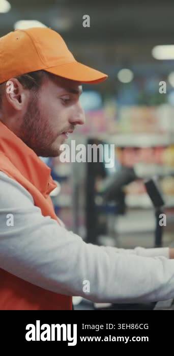 male night shift register operator scanning barcodes at checkout ...