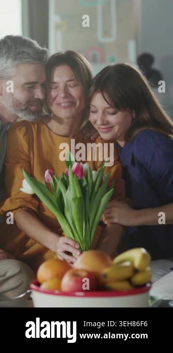 caucasian mother surprised by daughter, tulips, cozy living room ...