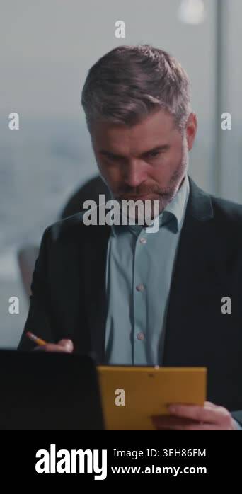 white financial consultant reading yellow folder by laptop, modern open ...