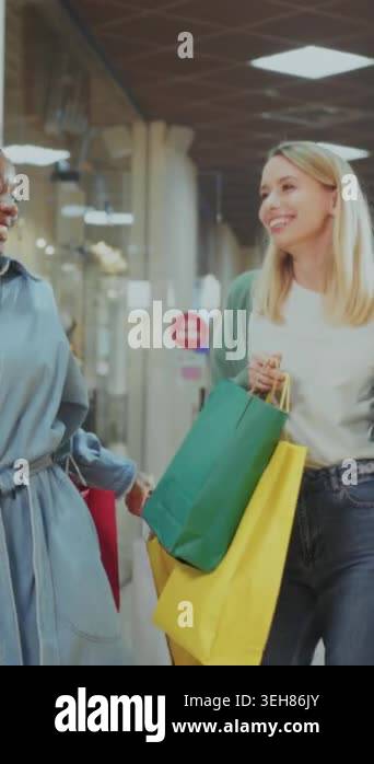 blonde white woman opening bag in mall corridor holding colorful paper ...