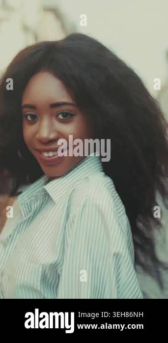 black woman joyful street portrait with voluminous hair, smiling at ...