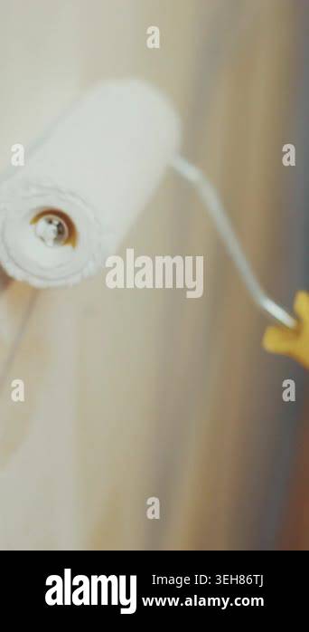 paint roller white paint on wall closeup of orange gloved hand gripping ...