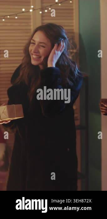woman arriving at cozy living room holiday party, guest greeting host ...