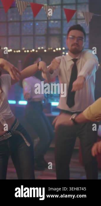 white businessman dancing at loft party, tie loosened, colleagues ...