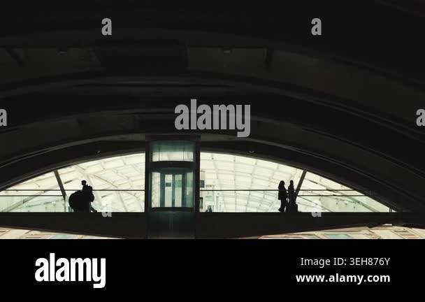 Two people walk across a bridge inside a modern structure. The large ...