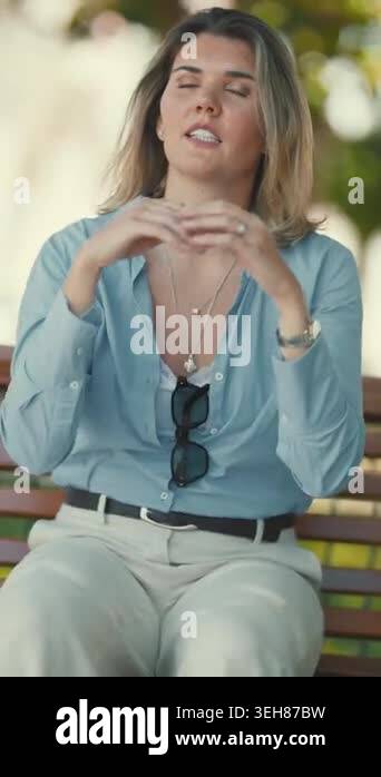 A woman shares her thoughts while sitting on a wooden bench in a park ...