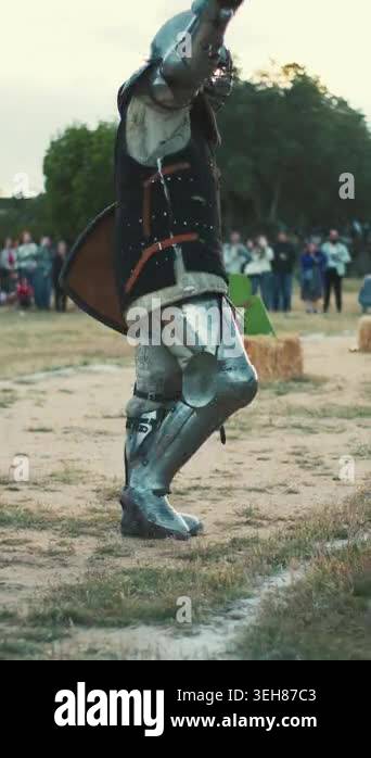 An armored knight walks on a grassy field at a local festival ...