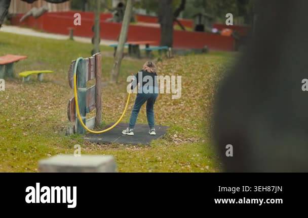 A child is having fun with a water hose in a park. The setting includes ...
