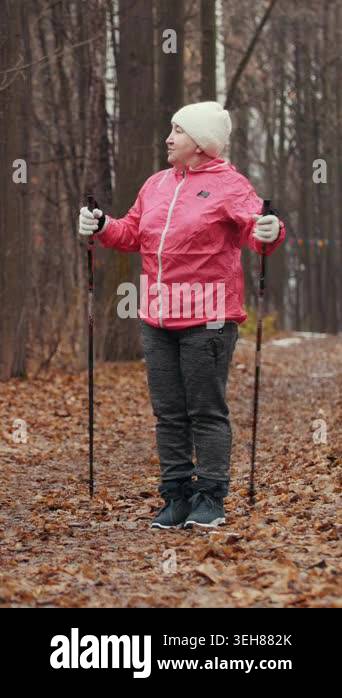 Elderly woman in autumn park doing warm up before nordic walking among ...