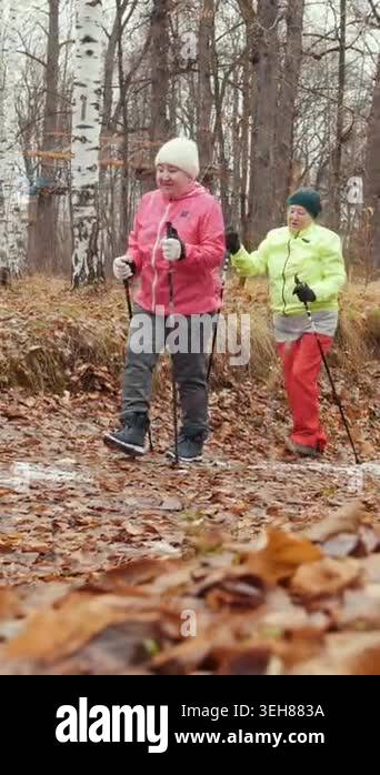 Two senior women in autumn park have training - nordic walking among ...