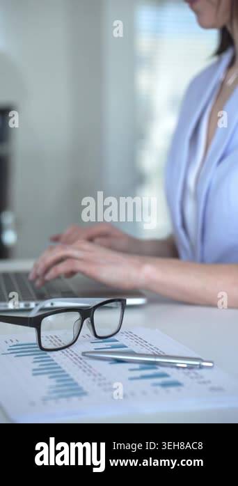 Professional woman working at a modern office desk, typing on a laptop ...