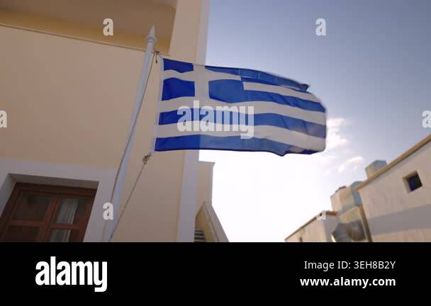 Greek national flag with blue and white stripes flutters in the wind on ...