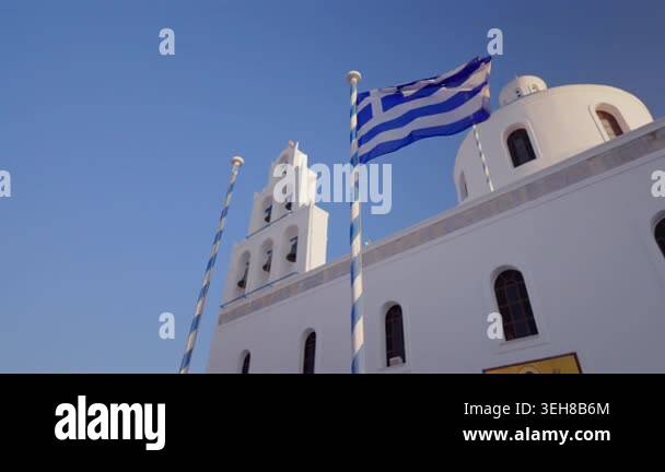 Greek national flag flutters on striped pole in front of traditional ...