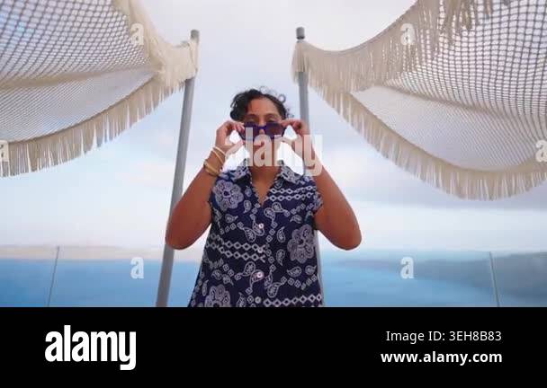 Stylish Indian woman in blue sunglasses and patterned shirt smiles at ...