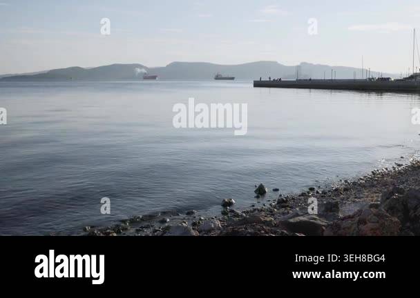 People are fishing on the pier with a background of ships and a calm ...