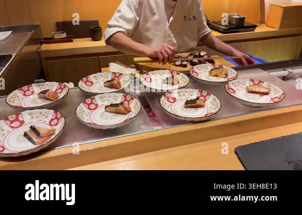 Chef slicing boiled octopus tentacle on wooden board in a high-end ...