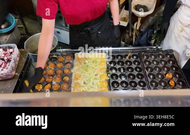 Street food vendor cooking traditional Japanese takoyaki octopus balls ...
