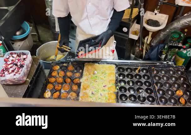 Street food vendor cooking traditional Japanese takoyaki octopus balls ...