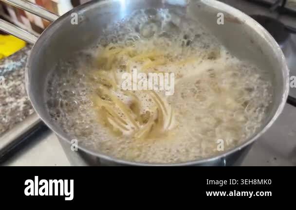 Delicious spaghetti cooking in a pot of vigorously boiling water on a ...