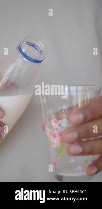 Hand pours milk from a bottle into a glass with flowers Stock Video ...