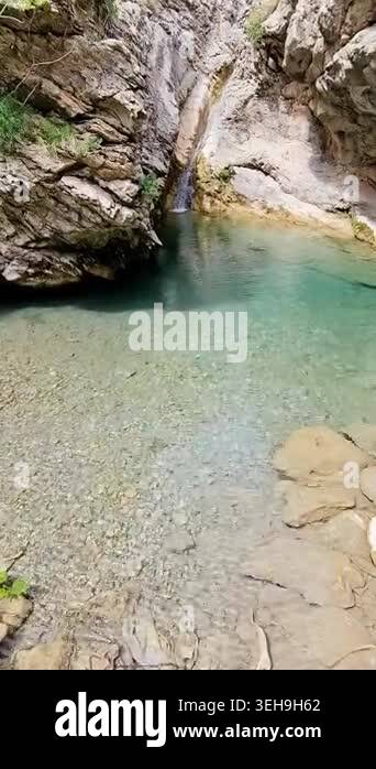 A weak waterfall flowing through rocky terrain in a natural landscape ...