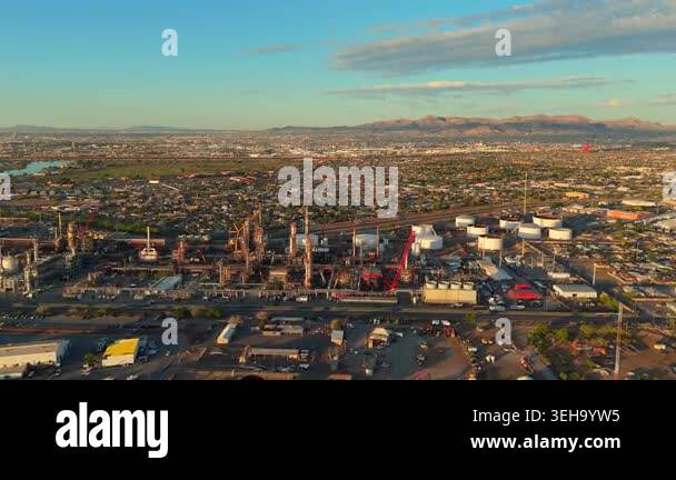 Warm evening aerial of storage tanks rail lines and desert mountain ...