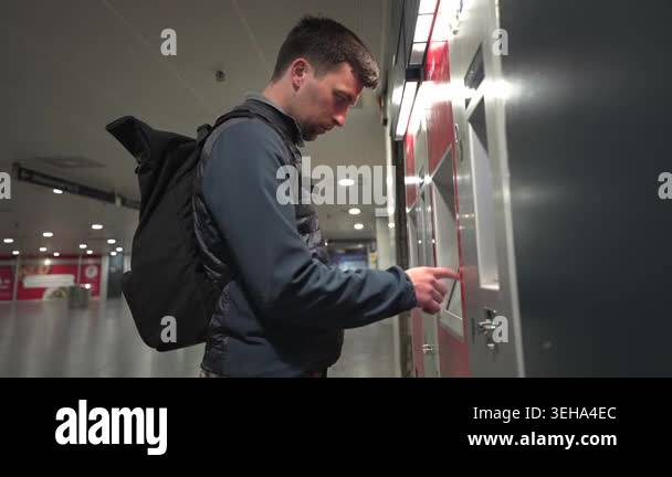 Passenger with smartphone and backpack buys a ticket from red DB ticket ...