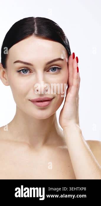 Young woman with smooth skin touching her face while looking at the ...