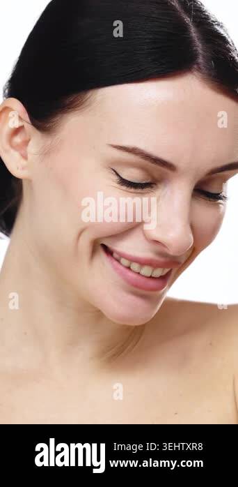 Woman smiling softly with closed eyes and natural makeup against a ...