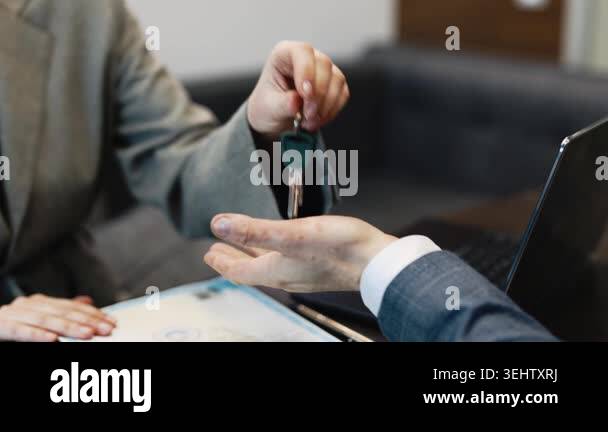 Person handing over car keys to another person in an office setting ...