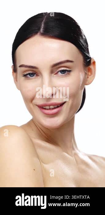 Smiling woman with fair skin and dark hair posing on a neutral ...