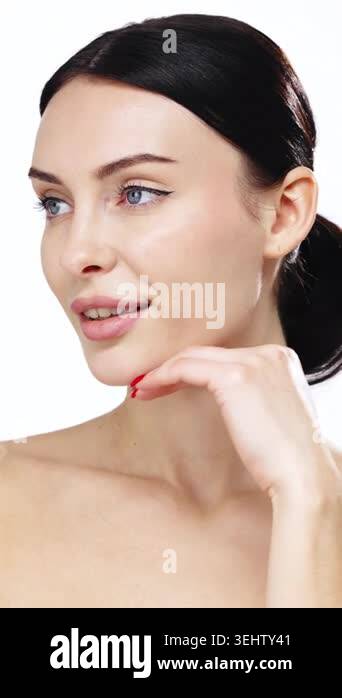 Young woman smiling with hand on chin against a plain white background ...
