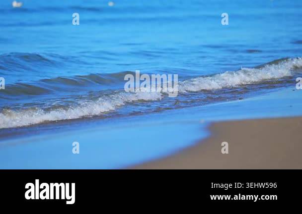 Gentle sea waves reaching the shore on a perfect summer day, serene ...